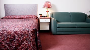 Quarto com cama, mesa de cabeceira, luminária e sofá.