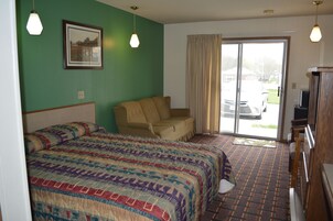 Quarto de hotel com cama, sofá, televisão e vista para o exterior.