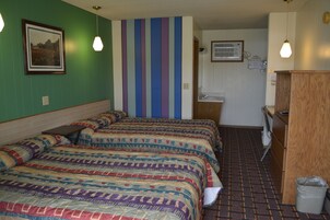 Quarto de hotel com duas camas, banheiro e pequena área de trabalho.