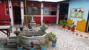 Pátio com uma fonte, plantas em vasos e piso de azulejos.
