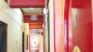 Um corredor com piso ladrilhado e uma porta vermelha com emblema decorativo.