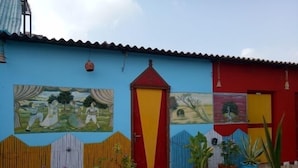 Um edifício com murais coloridos, uma porta vermelha e plantas em vasos.