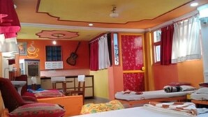 Um quarto com uma cama, uma escrivaninha e um violão na parede.