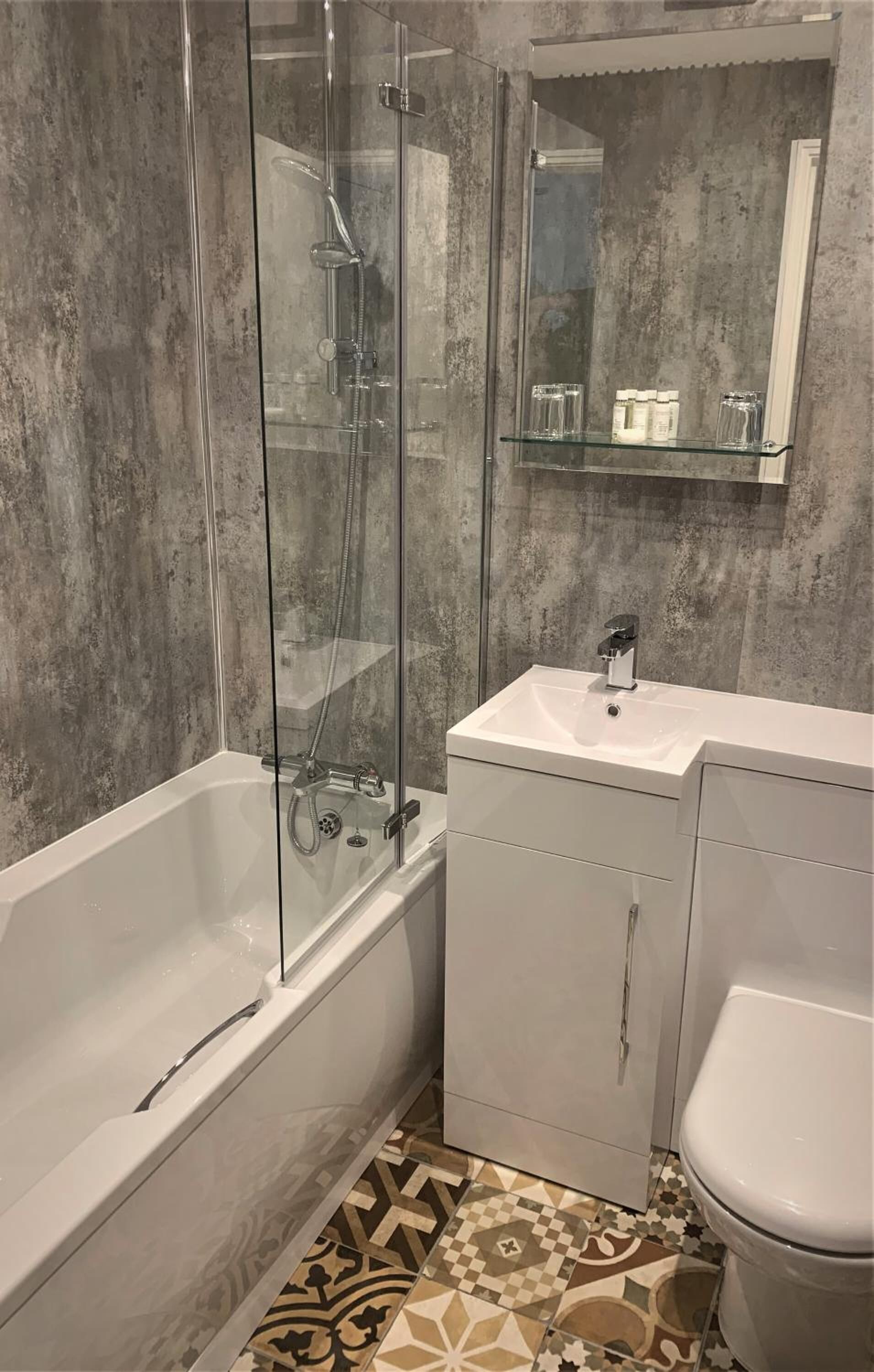 Casa de banho com chuveiro envidraçado, lavatório branco e sanita.