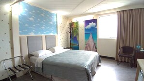 Quarto de hotel com cama, cadeira, escrivaninha e janela com cortinas.