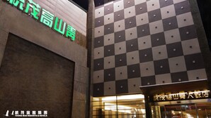 Fachada de hotel com padrão xadrez e letreiros iluminados.