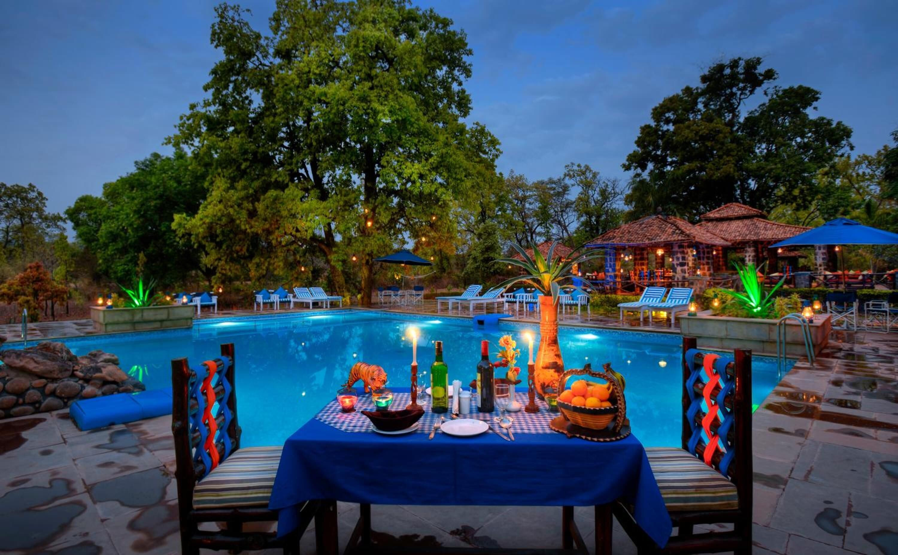 Disposição para refeições à beira da piscina, com mesa, cadeiras e piscina.