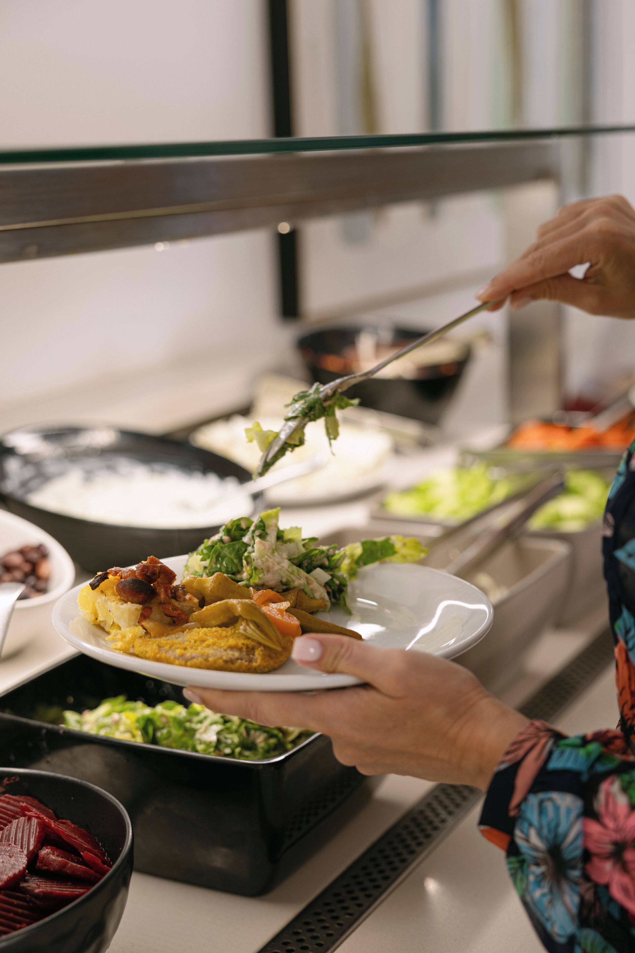 Buffet montado com diversos alimentos e uma pessoa se servindo.