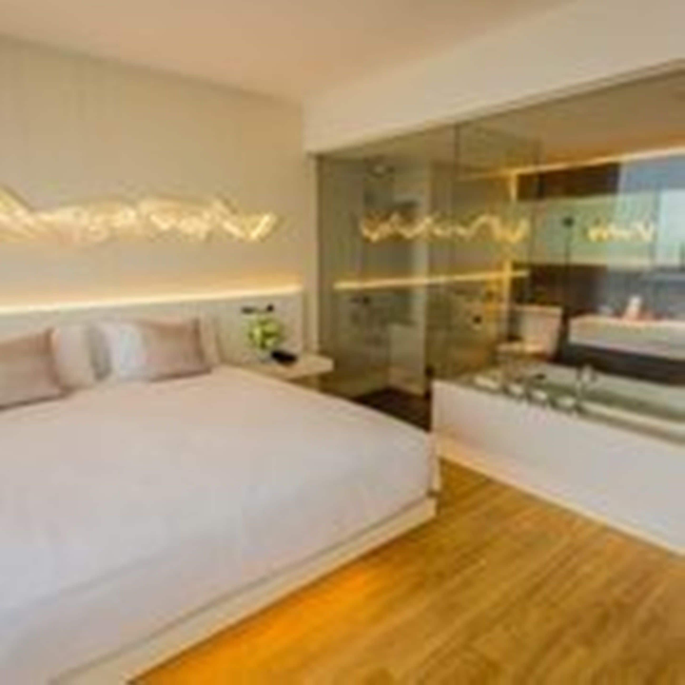 Quarto moderno com uma cama grande, divisória de vidro e vista para a cidade.