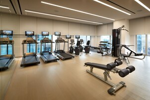 Uma academia moderna com esteiras, aparelho de supino e máquinas de musculação.