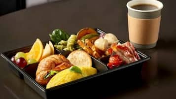 Uma bandeja de refeição com diversos alimentos e uma xícara de café sobre uma mesa.