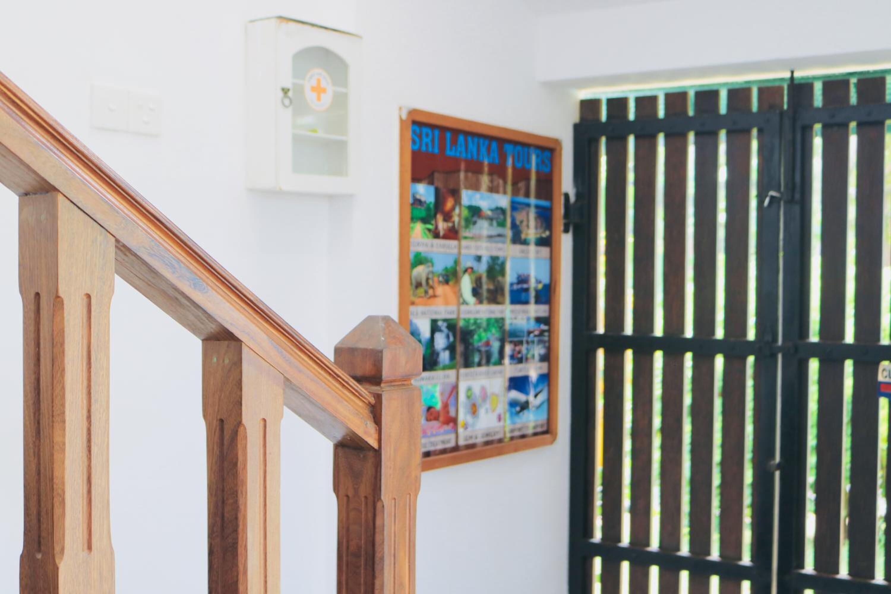 Uma escada de madeira leva a um quarto com um cartaz na parede promovendo passeios pelo Sri Lanka.