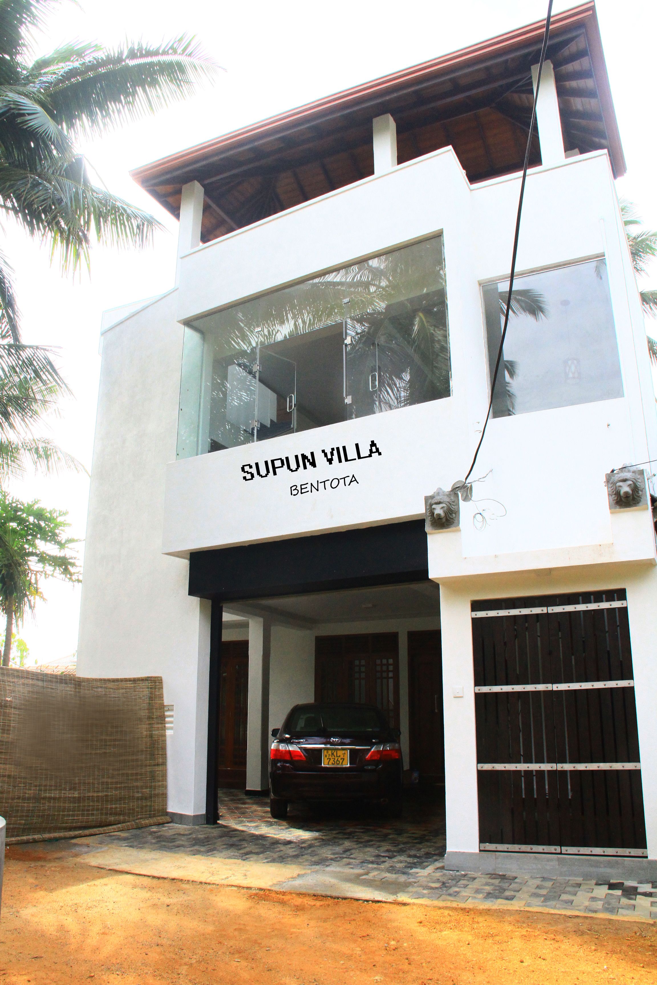 Um edifício de dois andares chamado "Supun Villa" com um carro estacionado na entrada.