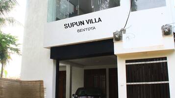 Um edifício de dois andares chamado "Supun Villa" com um carro estacionado na entrada.