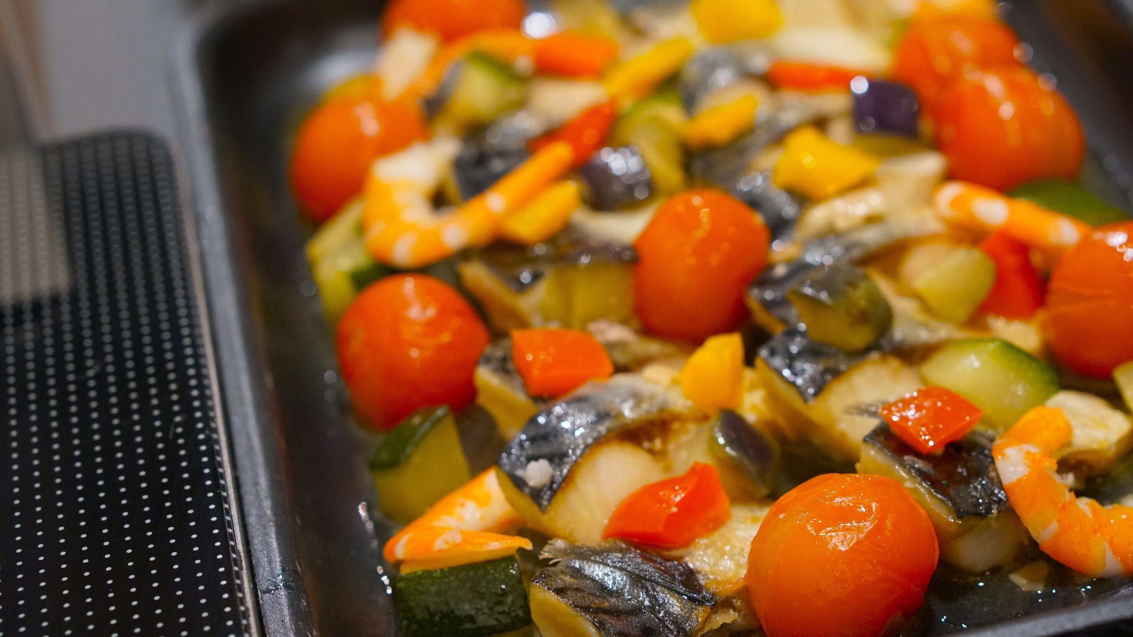 Uma travessa com legumes assados, incluindo abobrinha, pimentões e tomates cereja.