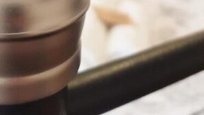 Um close-up de um objeto metálico, possivelmente parte de mobiliário ou decoração, com um fundo desfocado que sugere um ambiente interno.