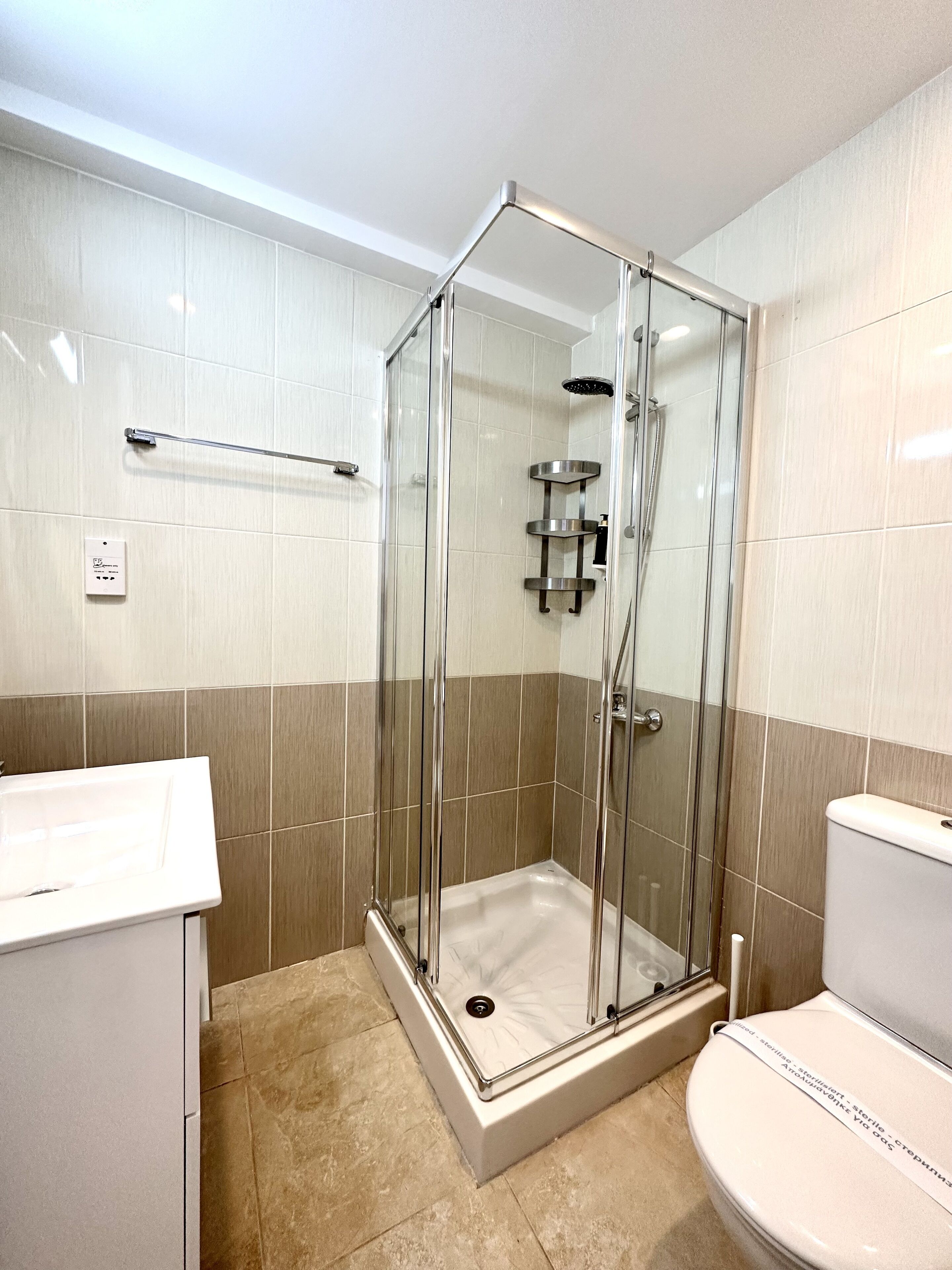 Uma casa de banho moderna com cabine de duche em vidro, lavatório branco e sanita.