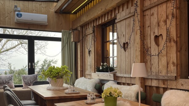 Um interior de madeira aconchegante com área de jantar, um candelabro e um ventilador de teto.