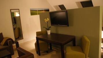 Uma sala de estar moderna com televisão de tela plana, uma mesa de jantar e assentos confortáveis.