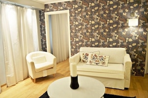Uma sala de estar com um sofá branco, uma poltrona branca e uma mesa de centro redonda.