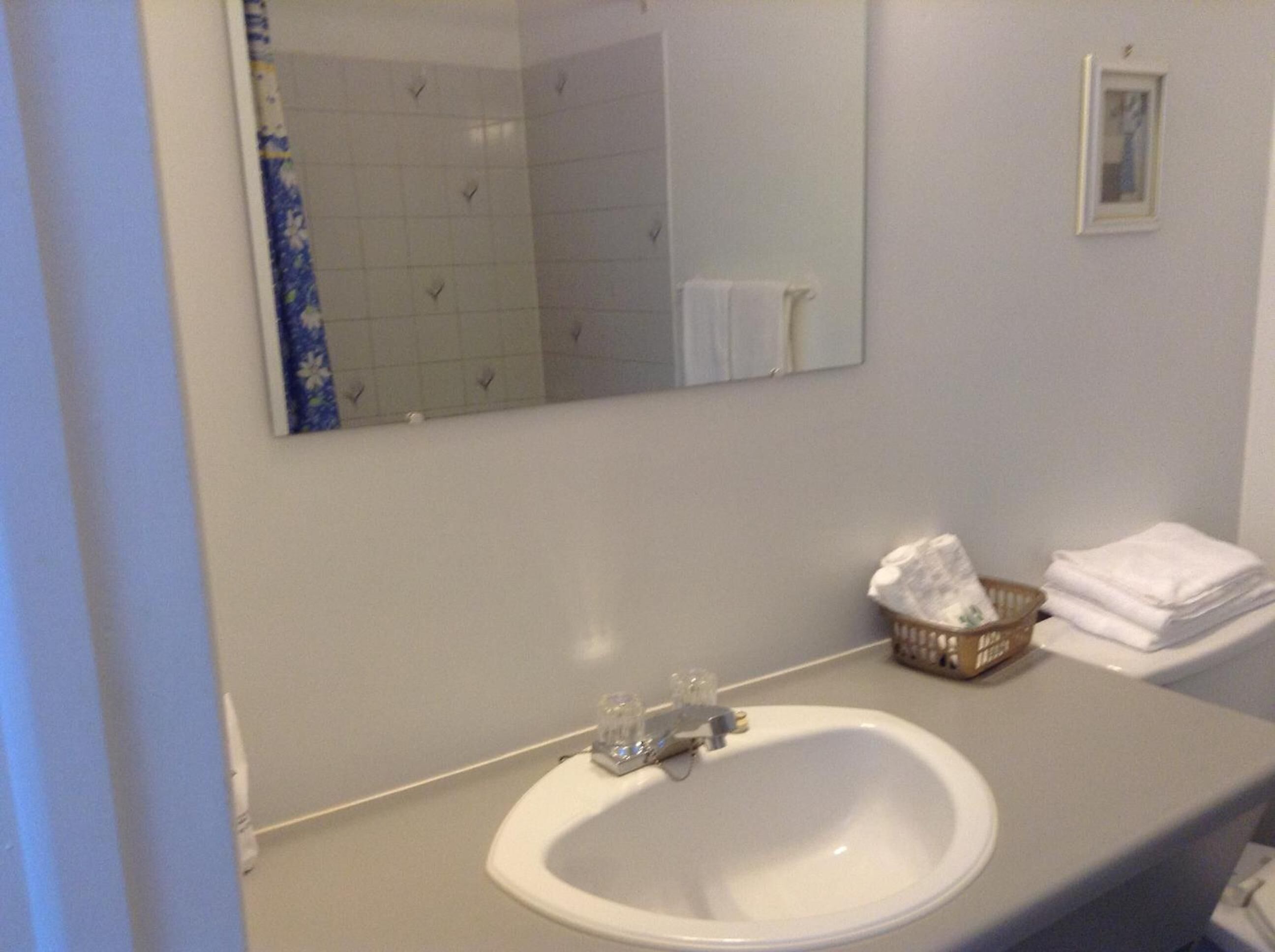 Uma casa de banho com uma pia branca, espelho e porta-toalhas.