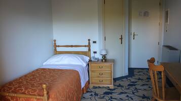 Quarto com cama, mesa de cabeceira, cadeira e porta.
