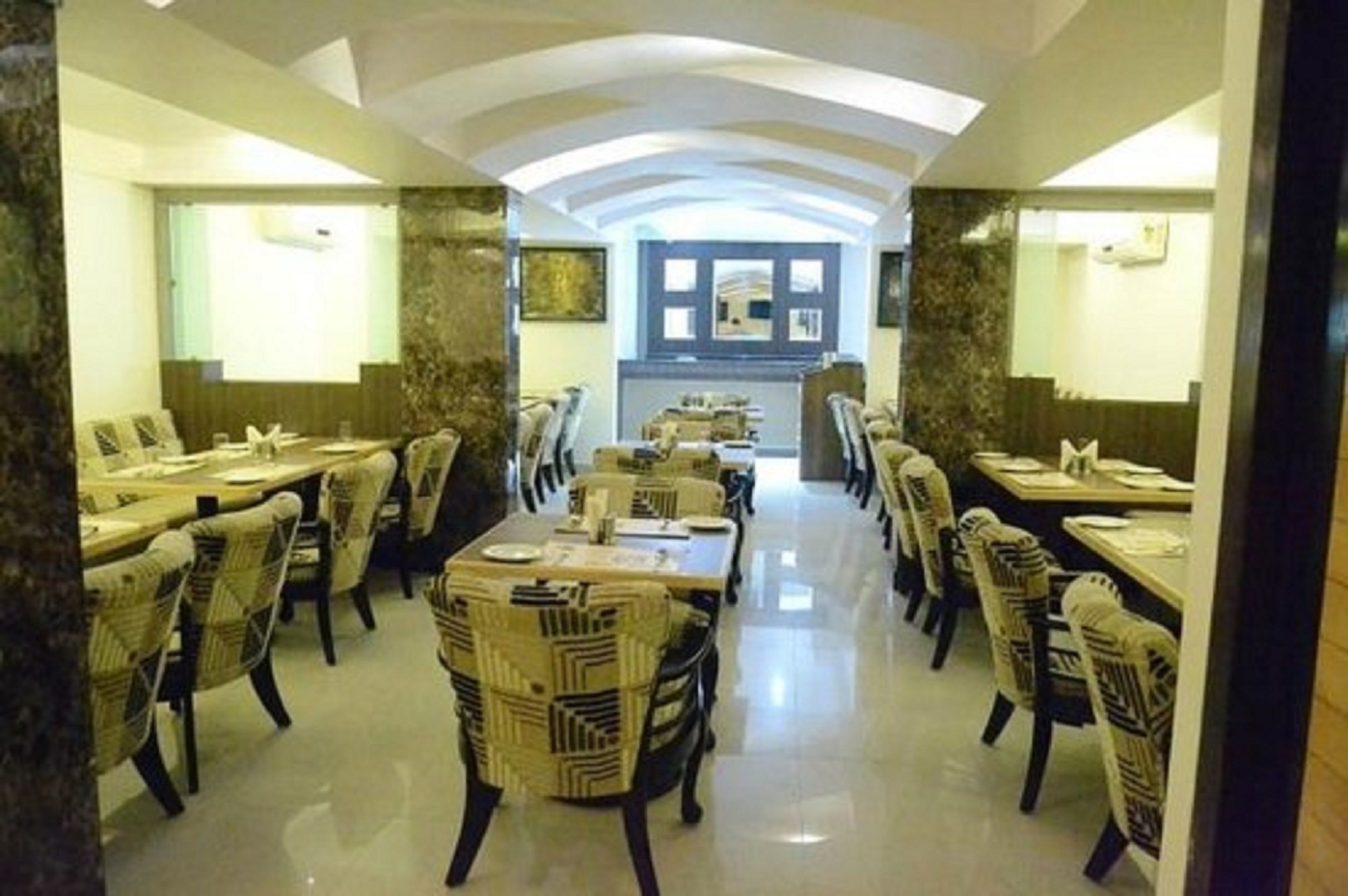 Restaurante com uma longa passagem central e várias mesas e cadeiras de ambos os lados.