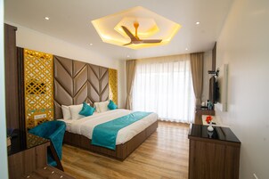 Quarto moderno com uma cama grande, um ventilador de teto e piso de madeira.
