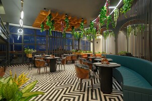 Um espaço moderno e interno com um chão de padrão geométrico, arranjos de assentos e plantas penduradas.