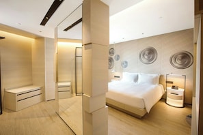 Quarto de hotel moderno com uma cama grande, mesas de cabeceira, espelho e arte decorativa na parede.