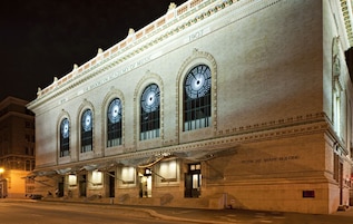 Um edifício histórico com janelas em arco e detalhes ornamentados, identificado como a Brooklyn Academy of Music.