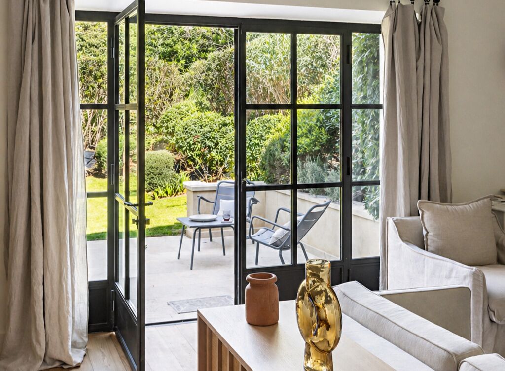 Quarto com uma grande porta de vidro deslizante que dá para uma área externa com mesa e cadeiras.