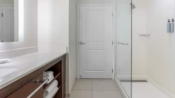 Uma casa de banho moderna com toucador branco, cabine de duche em vidro e porta branca.
