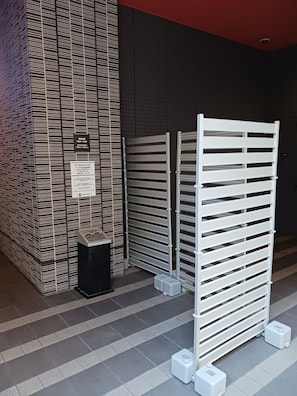 Entrada de hotel com balcão de check-in, mesa de recepção e parede com design estampado.