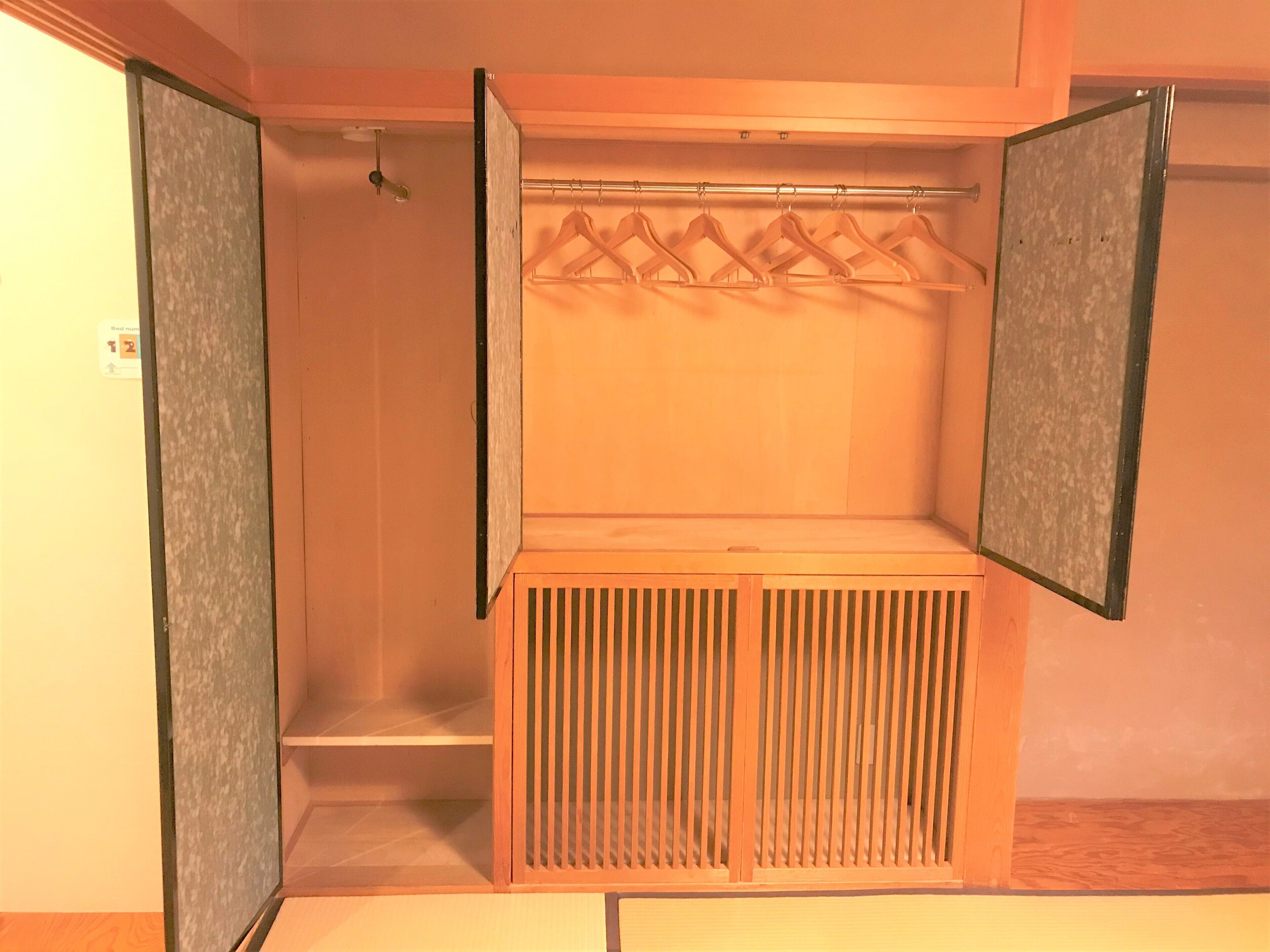 Um closet espaçoso com portas abertas, que inclui um cabideiro e um módulo de armazenamento com prateleiras.
