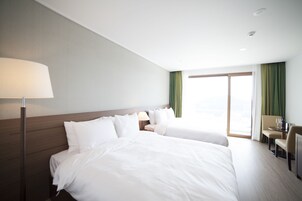 Quarto de hotel com duas camas, uma escrivaninha, uma cadeira e uma janela com cortinas.