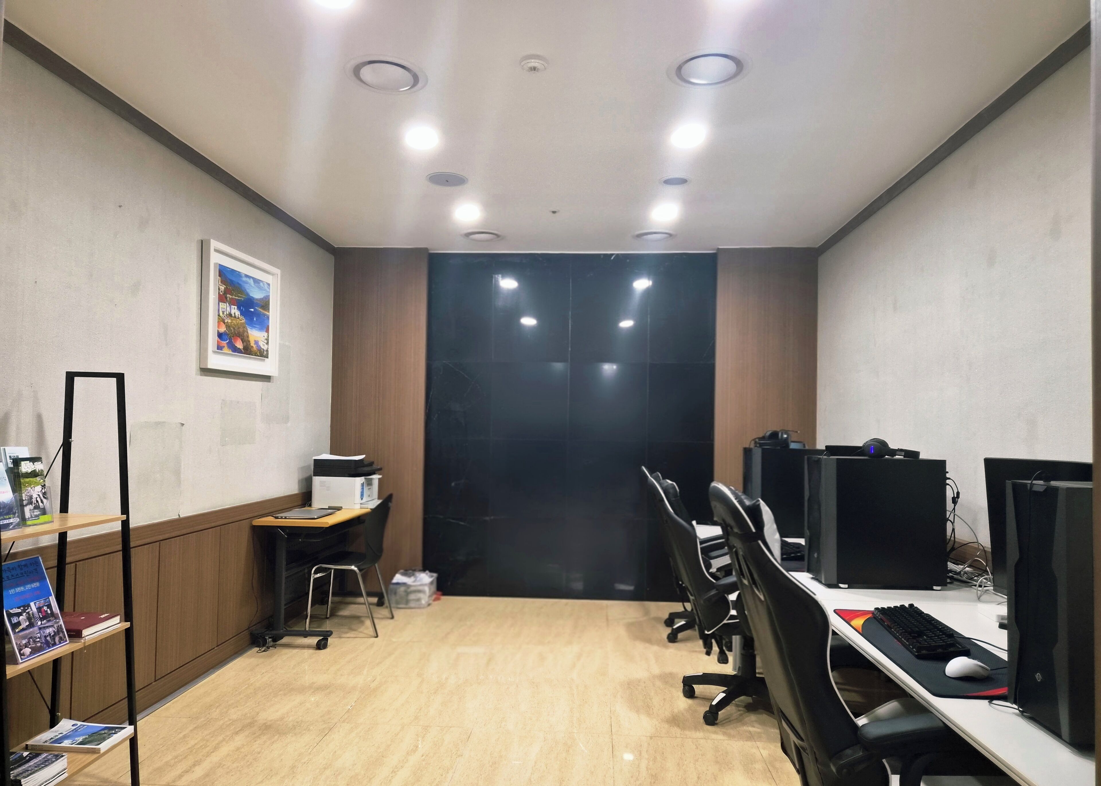 Um espaço de escritório moderno, com mesas, cadeiras, computadores e uma porta.