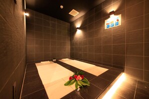 Um banheiro moderno com azulejos escuros, porta-toalhas e um quadro de informações fixado na parede.
