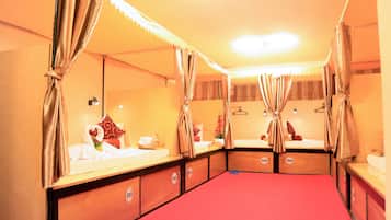 Quarto de hotel com quatro camas, cada uma com um número na lateral, e um tapete vermelho.