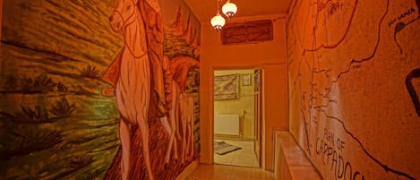 Um corredor com um mural de um cavaleiro e seu cavalo, um mapa na parede e um tapete estampado no chão.