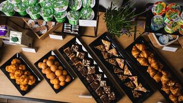 Diversos alimentos como iogurte, doces e sobremesas expostos em uma mesa de madeira.