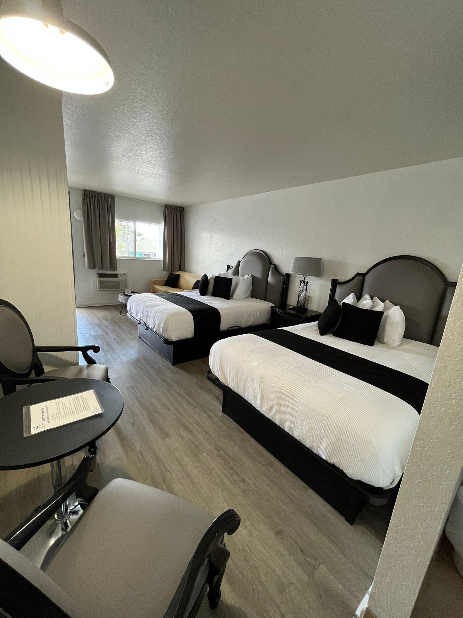 Quarto de hotel com duas camas, uma escrivaninha e uma cadeira.
