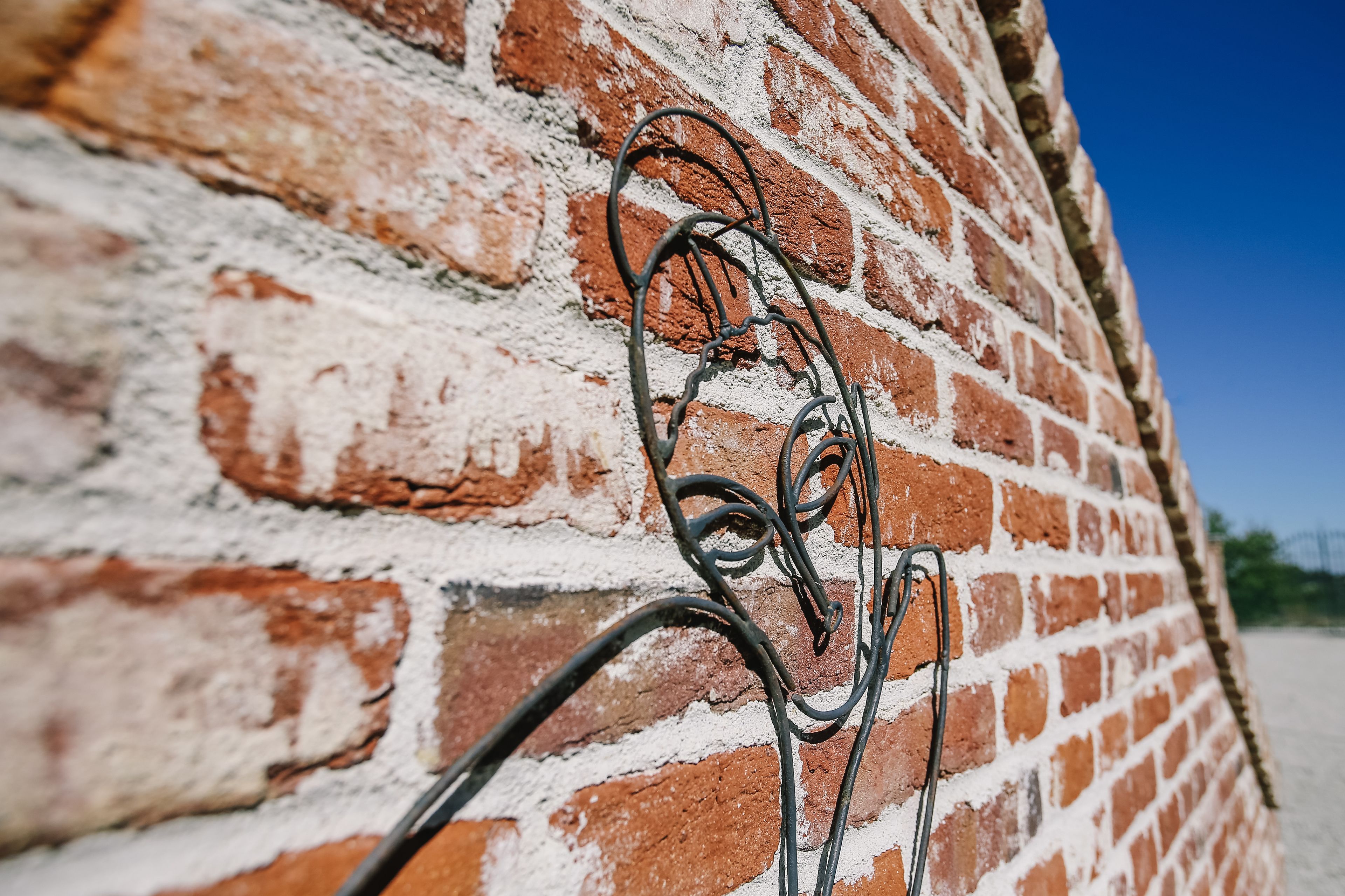 Close-up de uma escultura metálica em frente a uma parede de tijolos.