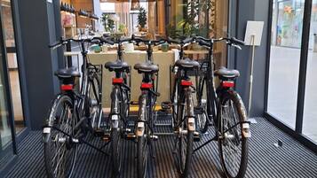 Um interior moderno com uma estação de aluguel de bicicletas, janelas amplas e um lustre central.