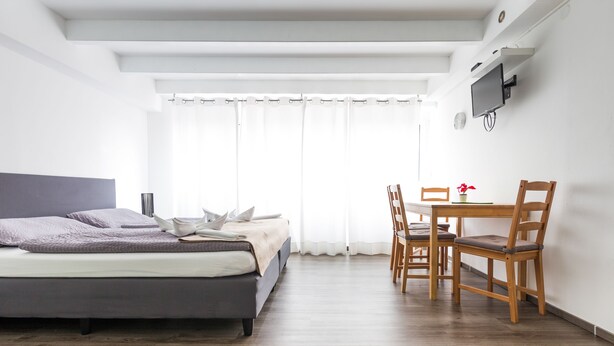 Quarto de hotel moderno com cama, mesa de jantar de madeira e cadeiras.