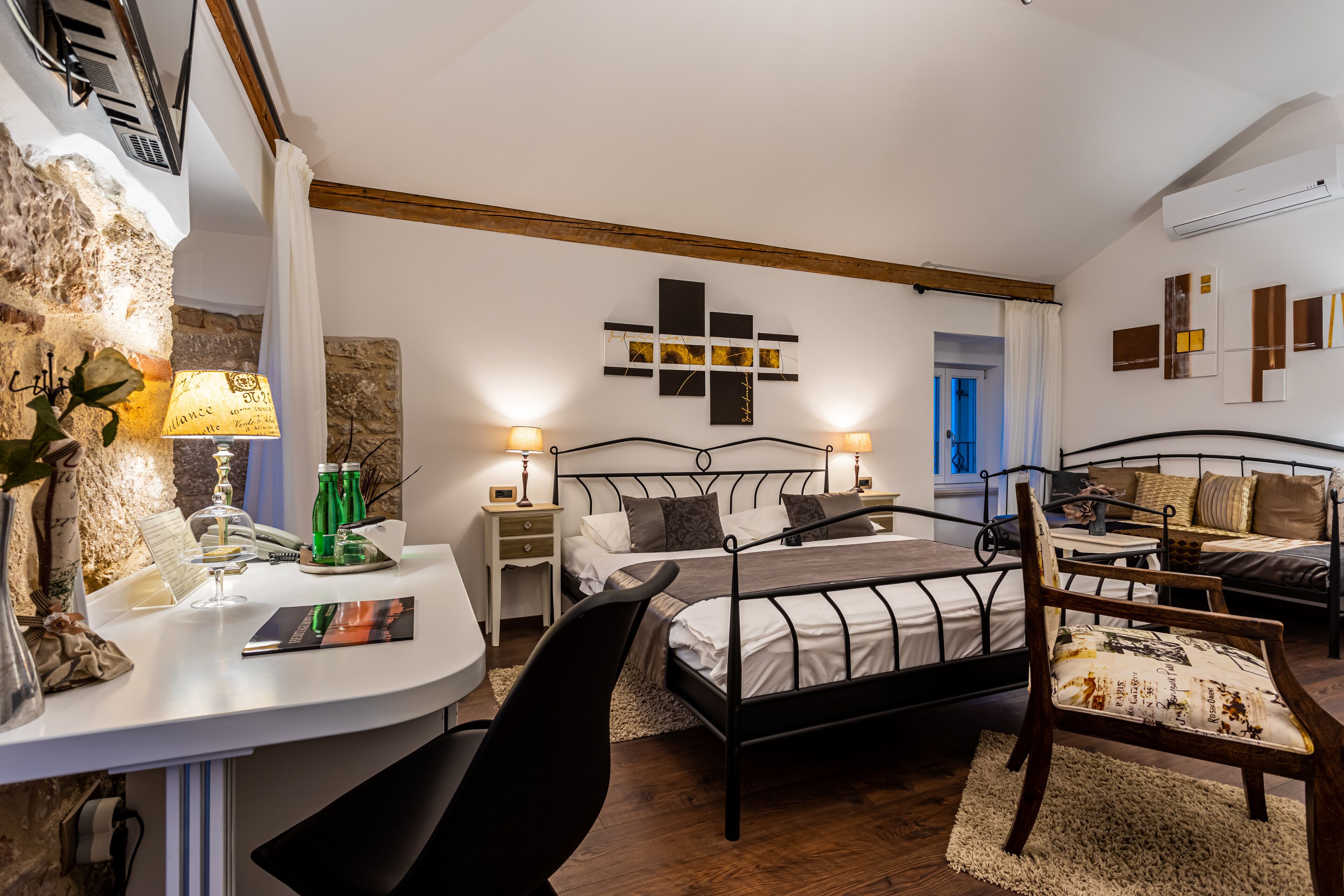 Quarto com cama, mesas de cabeceira, escrivaninha e uma cadeira.