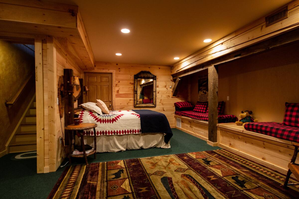 Um quarto de cabana de madeira aconchegante, com uma cama, um banco e um espelho.