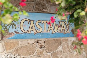 Um muro de pedra com uma placa pintada que diz 'CASTAWAY'.