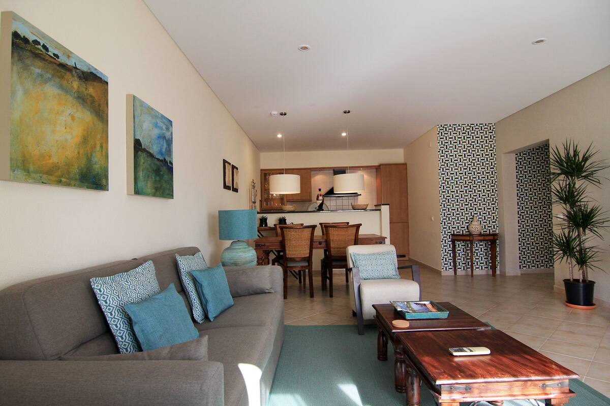 Uma sala de estar com sofá, mesa de centro e um espaço de jantar com cadeiras e mesa.