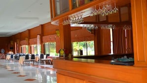Um hall de hotel espaçoso com um balcão de recepção extenso, várias mesas e cadeiras, e amplas janelas com vista para o exterior.